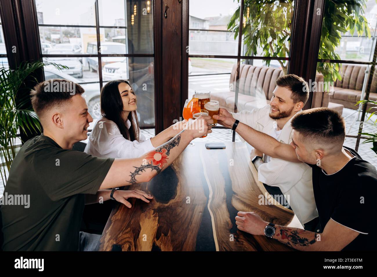 Happy group of friends drinking and clinking with beer and cocktails at ...