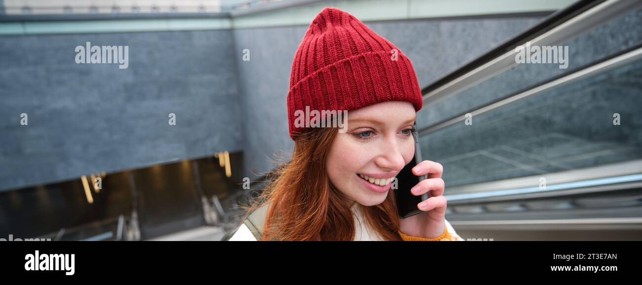 Portrait of happy redhead woman walking around town with smartphone ...