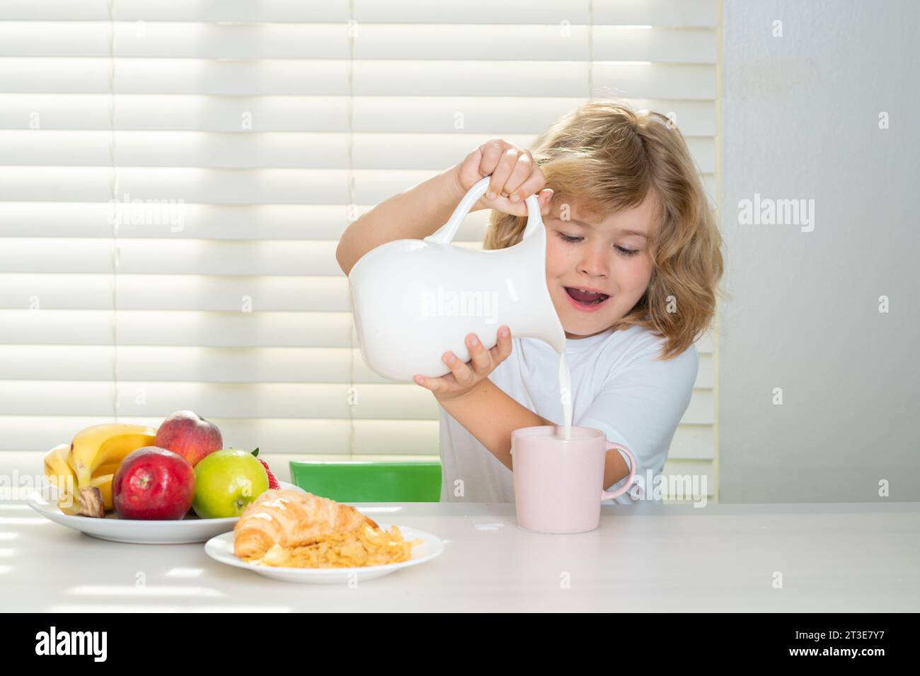 Fuuny little boy pouring whole cows milk for breakfast. Portrait of ...