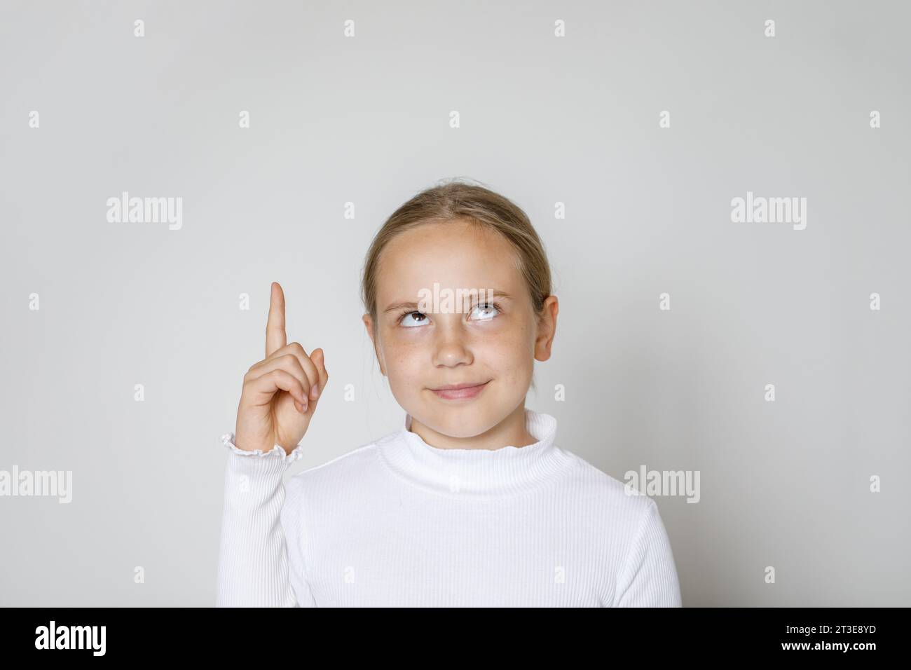 Cute child pointing finger up on white studio wall background Stock ...