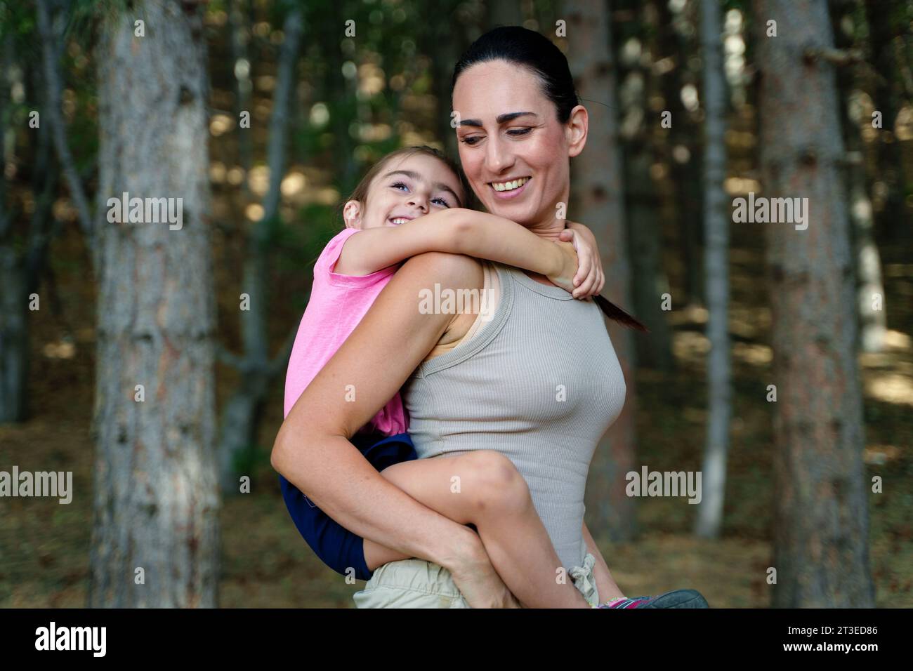 A joyful mother and her young daughter share a close and loving embrace amidst the serene ...