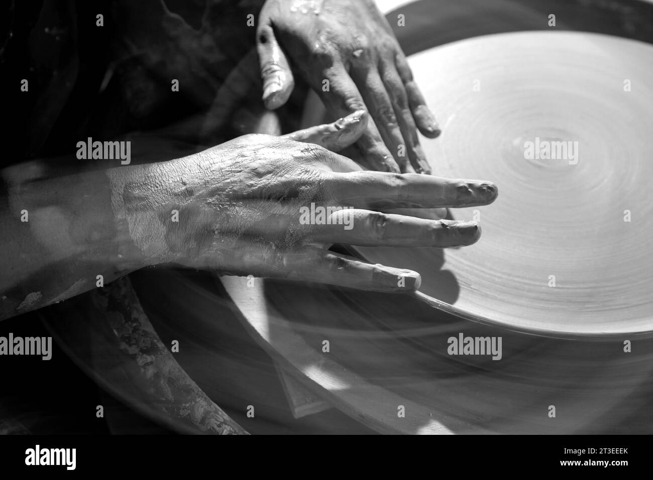 Black and white image of the hands of a young female potter throwing ...