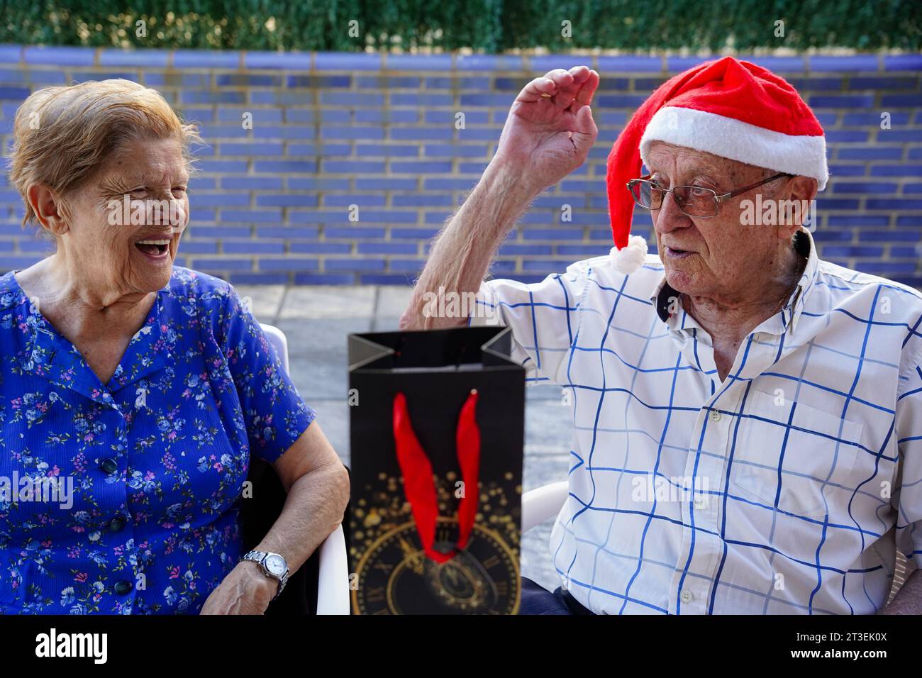 older marriage with a christmas gift with a santa claus hat. Elderly ...