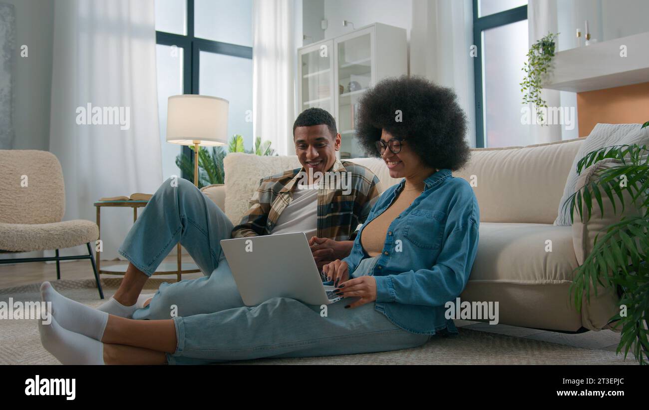 African American couple on floor at home using online laptop computer ...