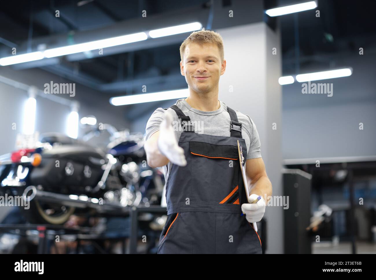 Young smiling master man in uniform stretches arms forward in car ...
