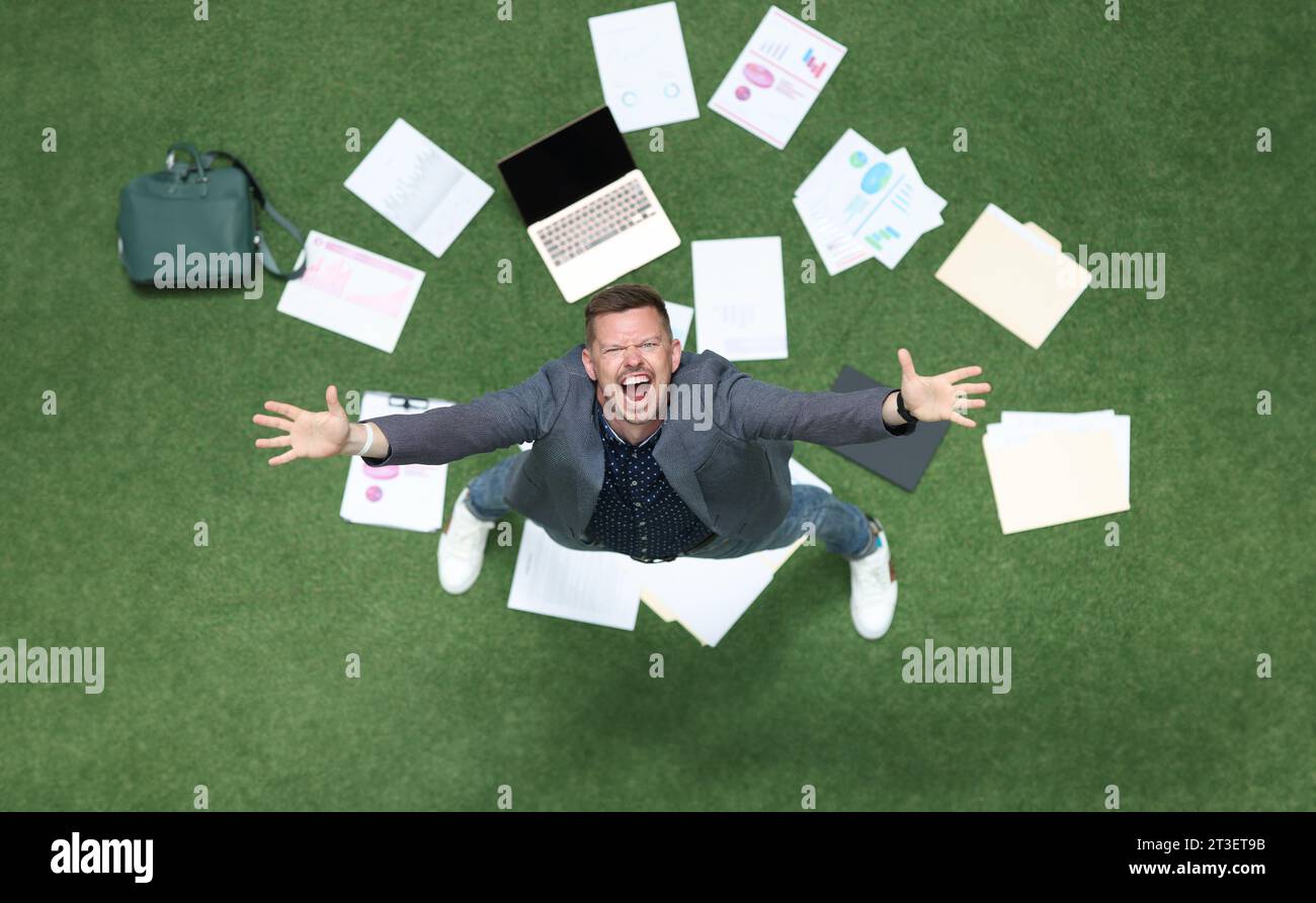 Man in suit throwing papers on green grass and yelling with his hands ...