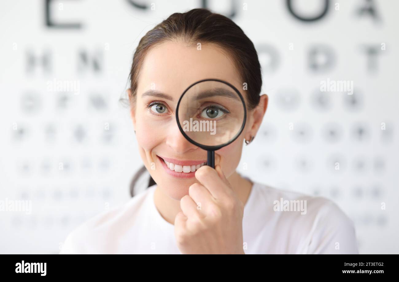Woman optometrist holding magnifying glass in eyes against background ...