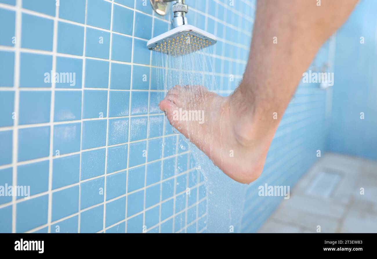 Man washing his feet from sand under shower on beach closeup Stock ...