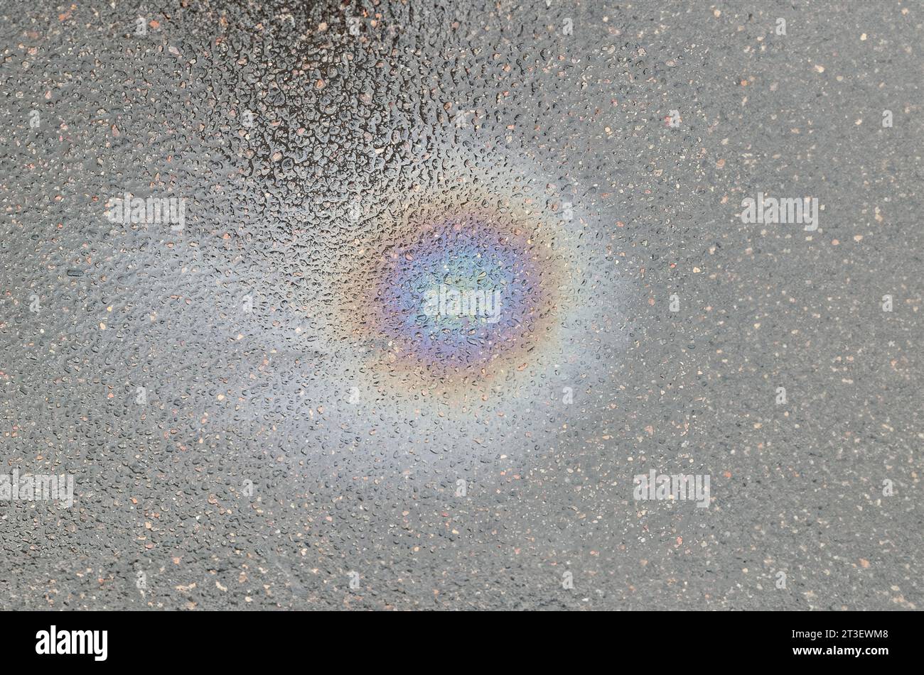 Bright rainbow spot on wet asphalt from gasoline closeup background ...