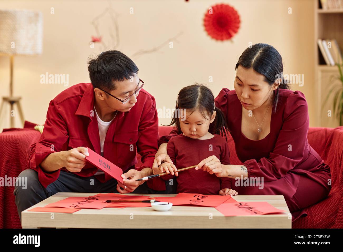 Portrait of Chinese family writing with ink and brush doing traditional ...