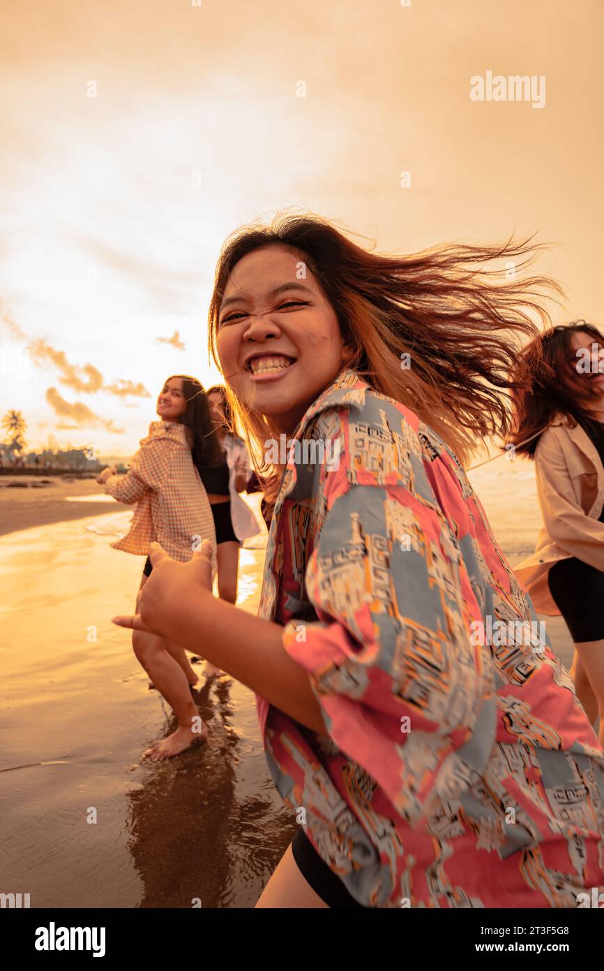 a group of Asian teenagers in shirts running with their friends with ...