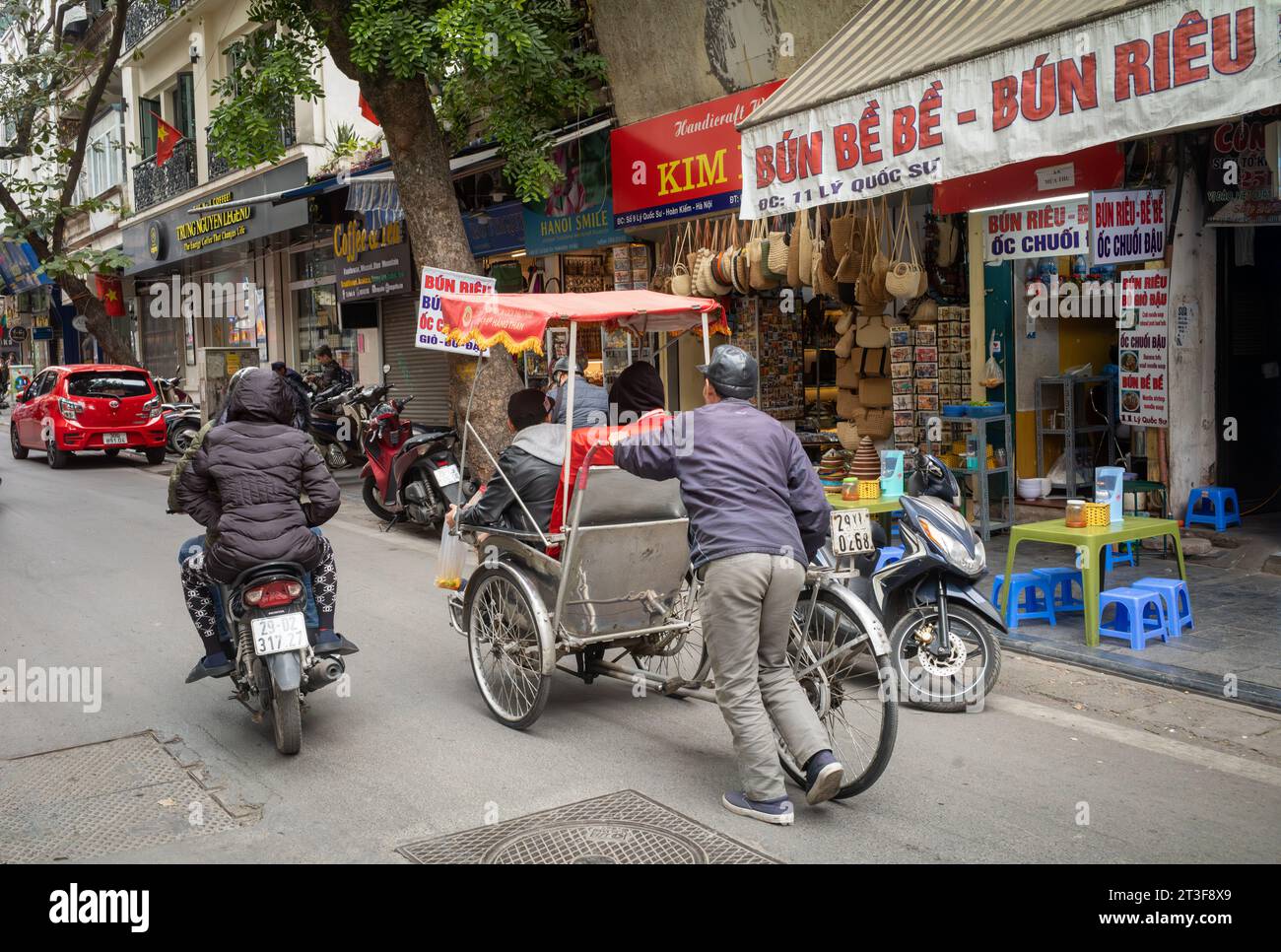 A traditional cyclo pedicab driver pushes his cyclo with two passengers ...