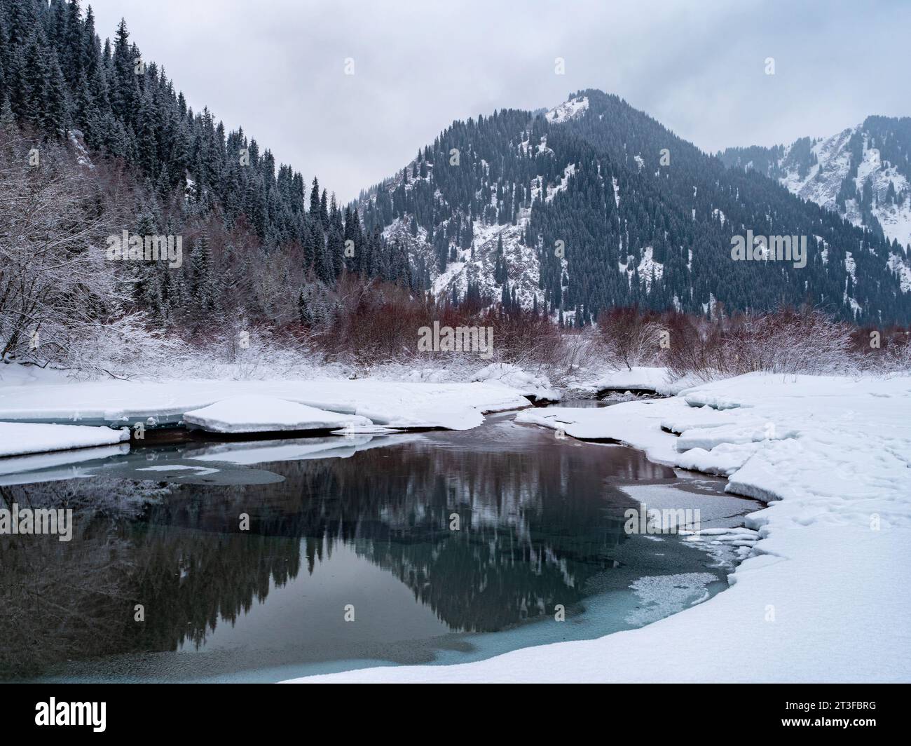 Winter landscape with mountains and an unfrozen river with reflection ...