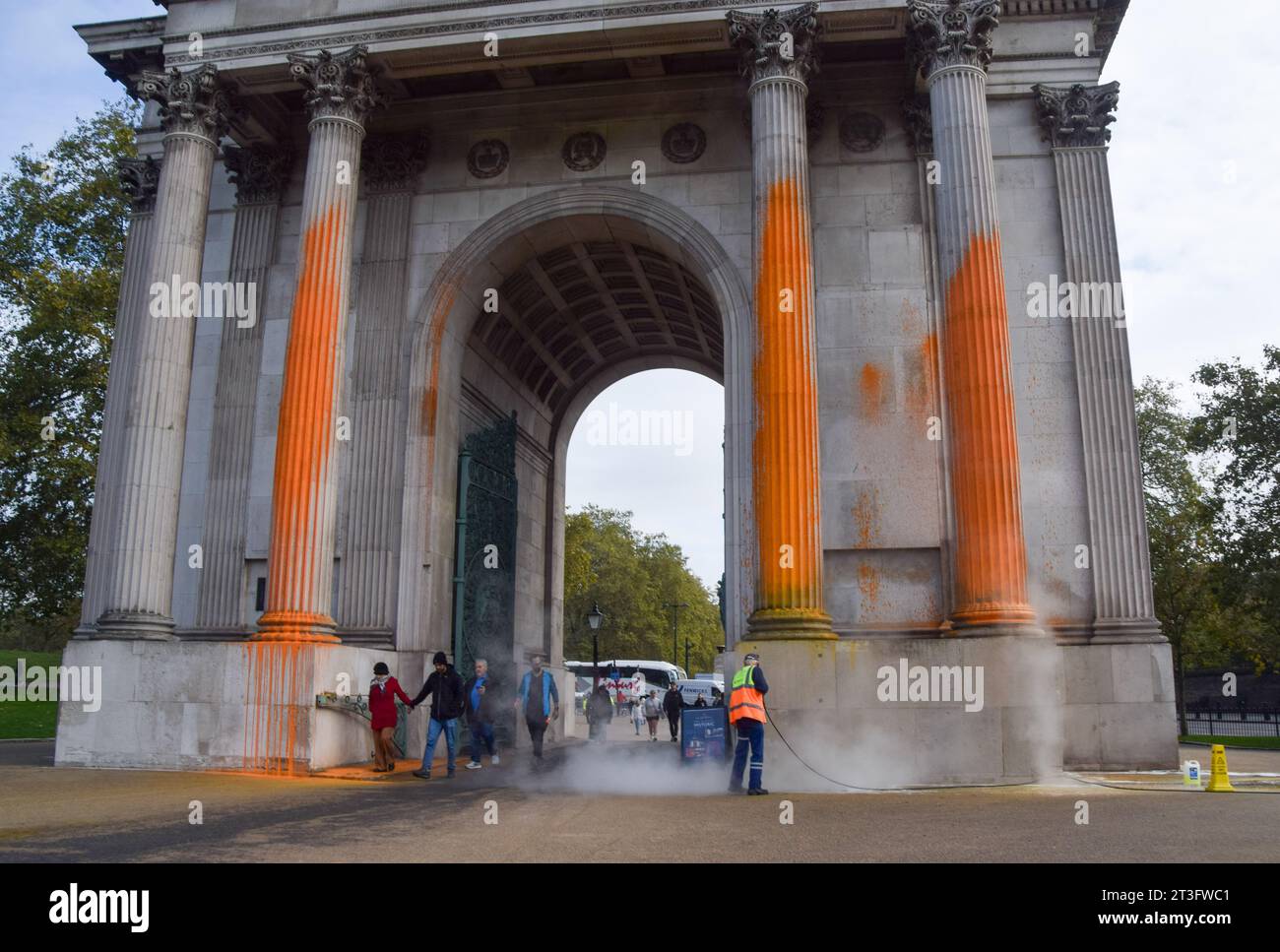London, UK. 25th October 2023. A worker cleans the orange paint sprayed ...