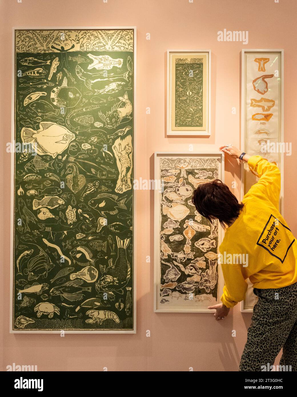 London, UK. 25 October 2023. A staff member with works by Jake Garfield ...