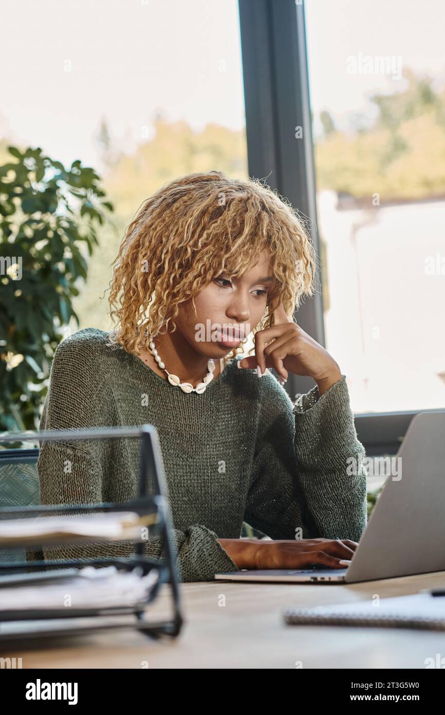 focused young african american woman with curly hair looking at her ...
