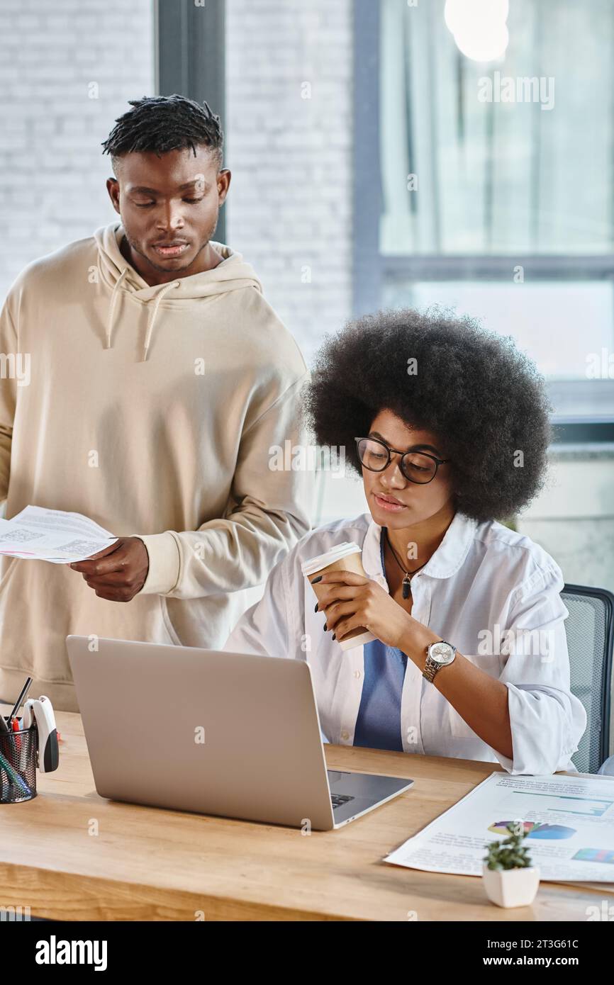 african american colleagues working hard with laptop and papers with ...