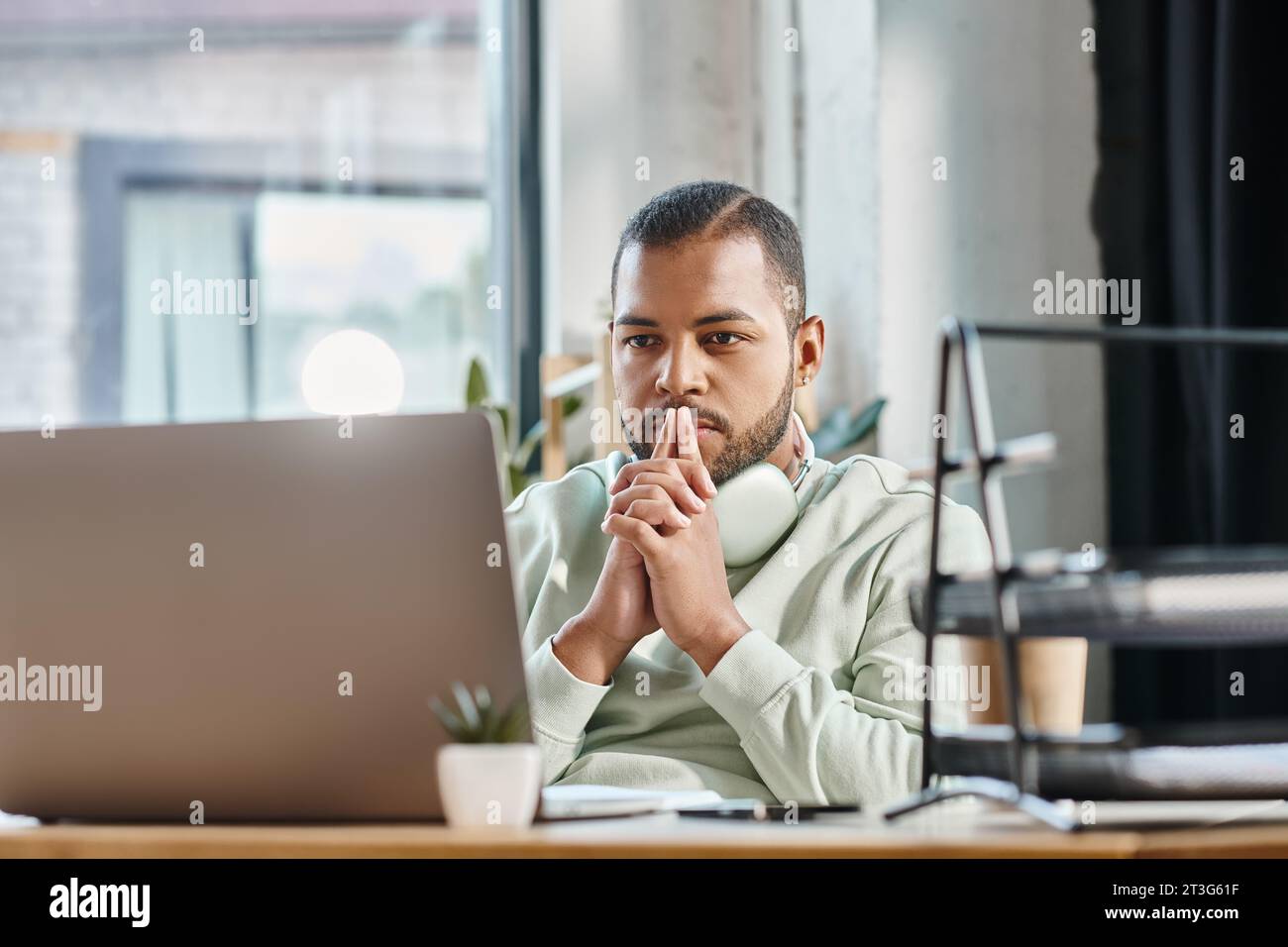 thoughtful young man looking seriously at his laptop with fingers near ...
