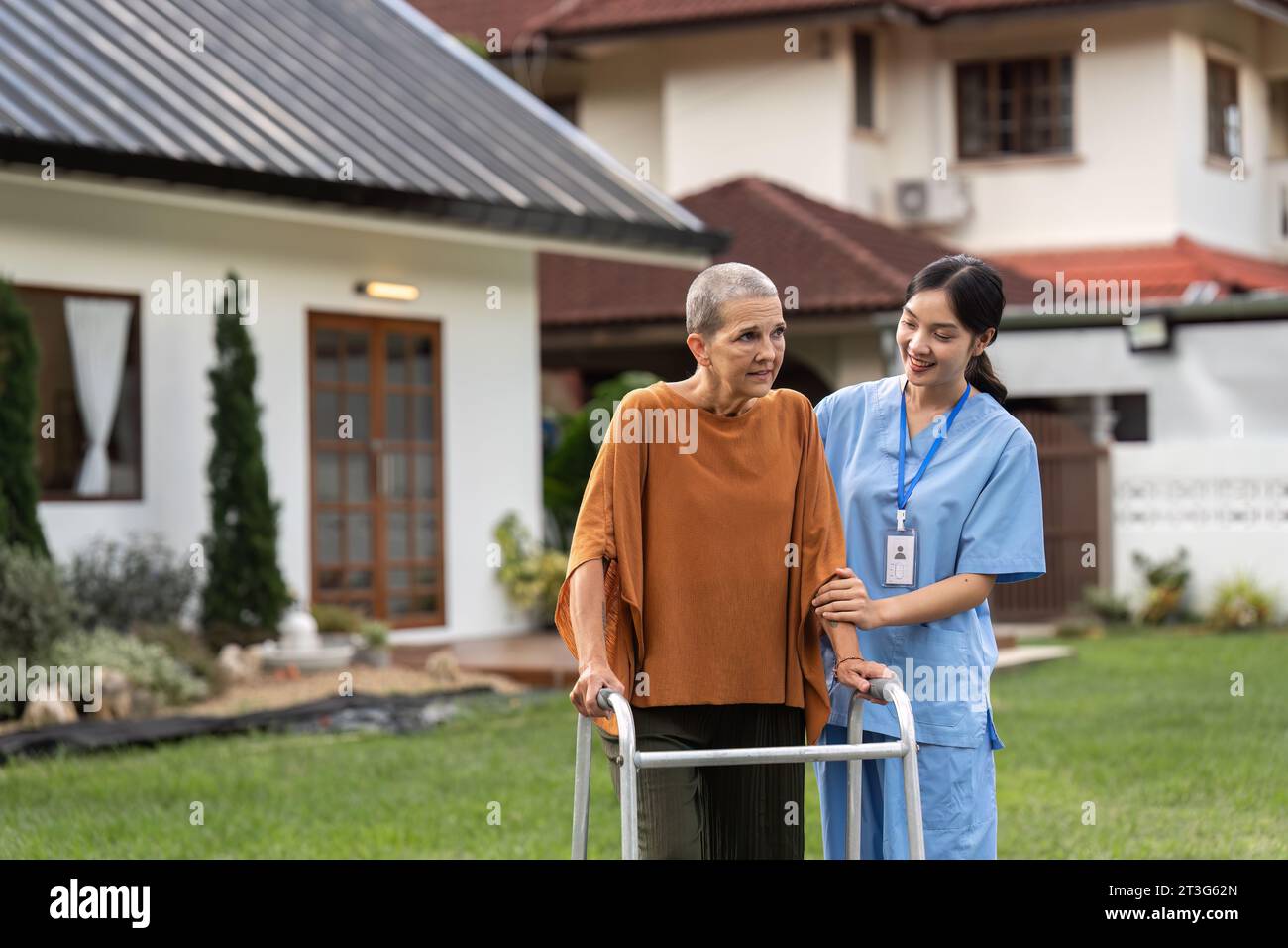 Nurse or caregiver help elderly walk by using walker in garden Stock ...