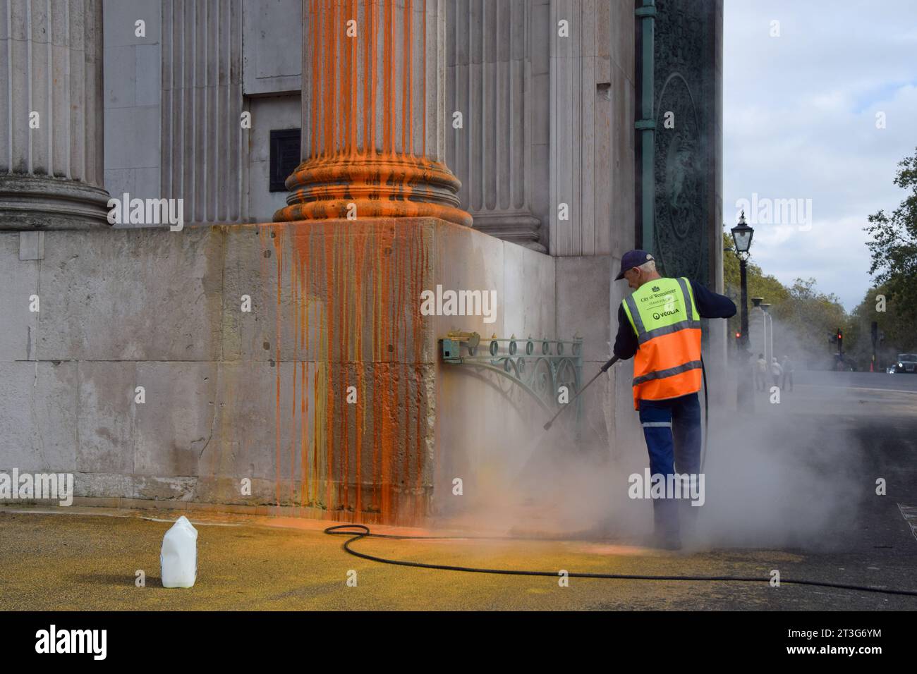 London, UK. 25th October 2023. A worker cleans the orange paint sprayed ...