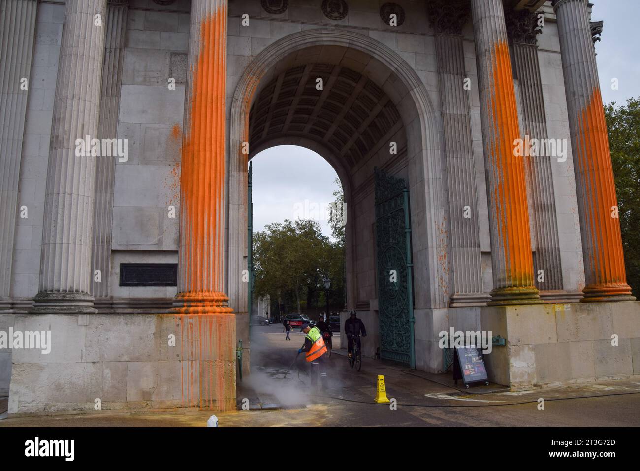 London, UK. 25th October 2023. A worker cleans the orange paint sprayed ...