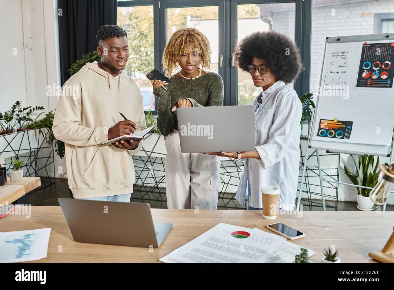 cheerful young friends working on their project with laptops with ...