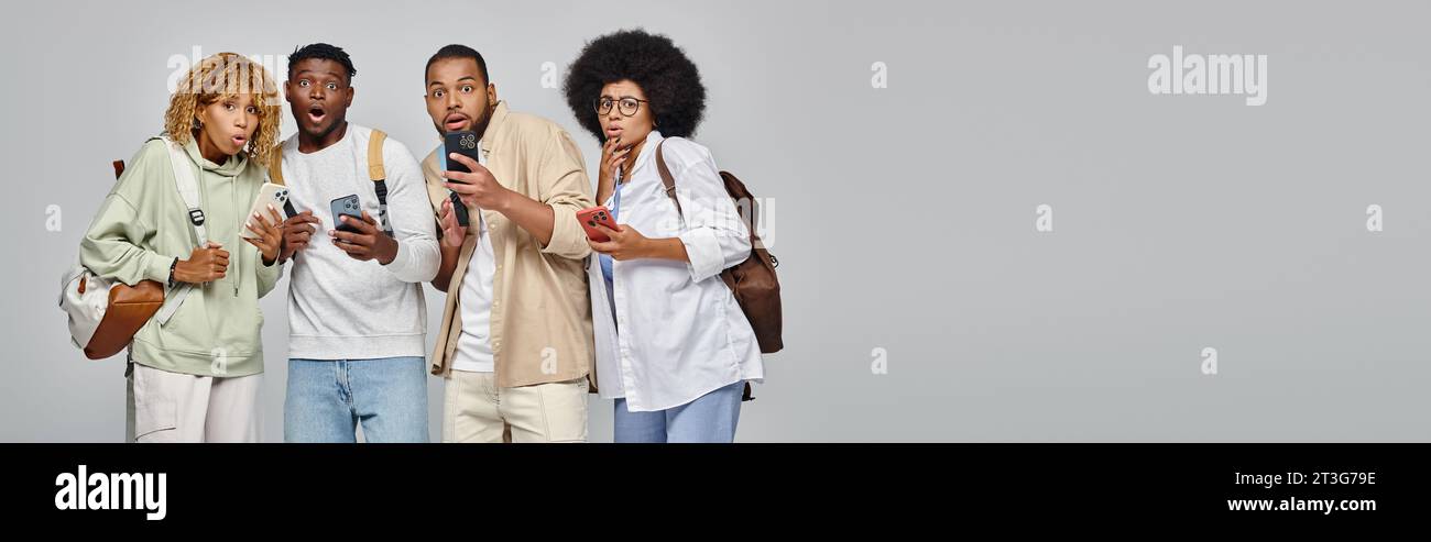 shocked friends with backpacks holding phones and looking astonishingly ...