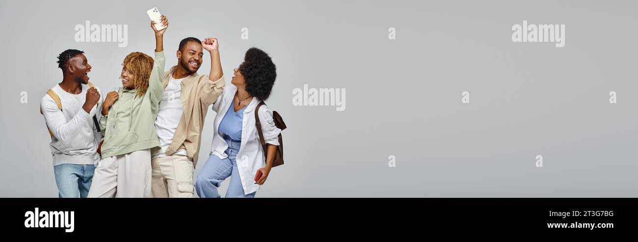 young students cheering and smiling joyfully posing on gray background ...