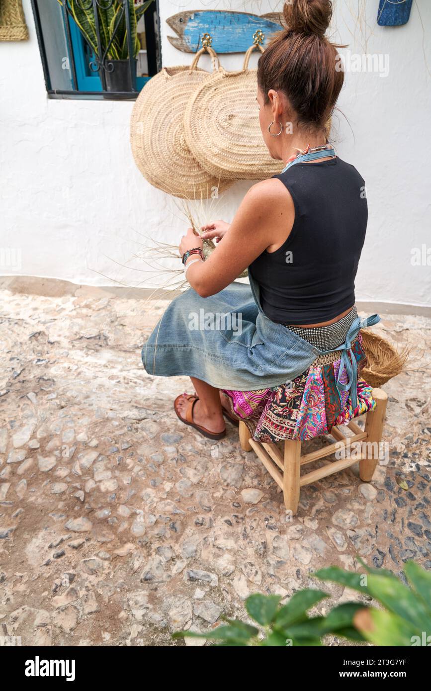 Rear view of Hispanic woman weaving a basket with esparto fibers ...