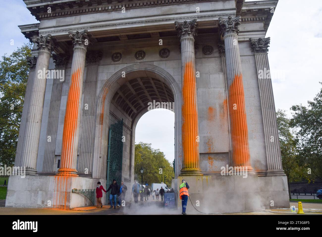 London, UK. 25th October 2023. A worker cleans the orange paint sprayed ...