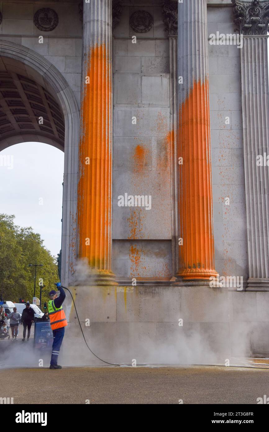 London, UK. 25th October 2023. A worker cleans the orange paint sprayed ...
