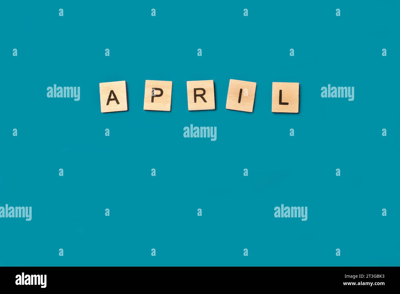 April single word made with wooden letter blocks on an blue background ...