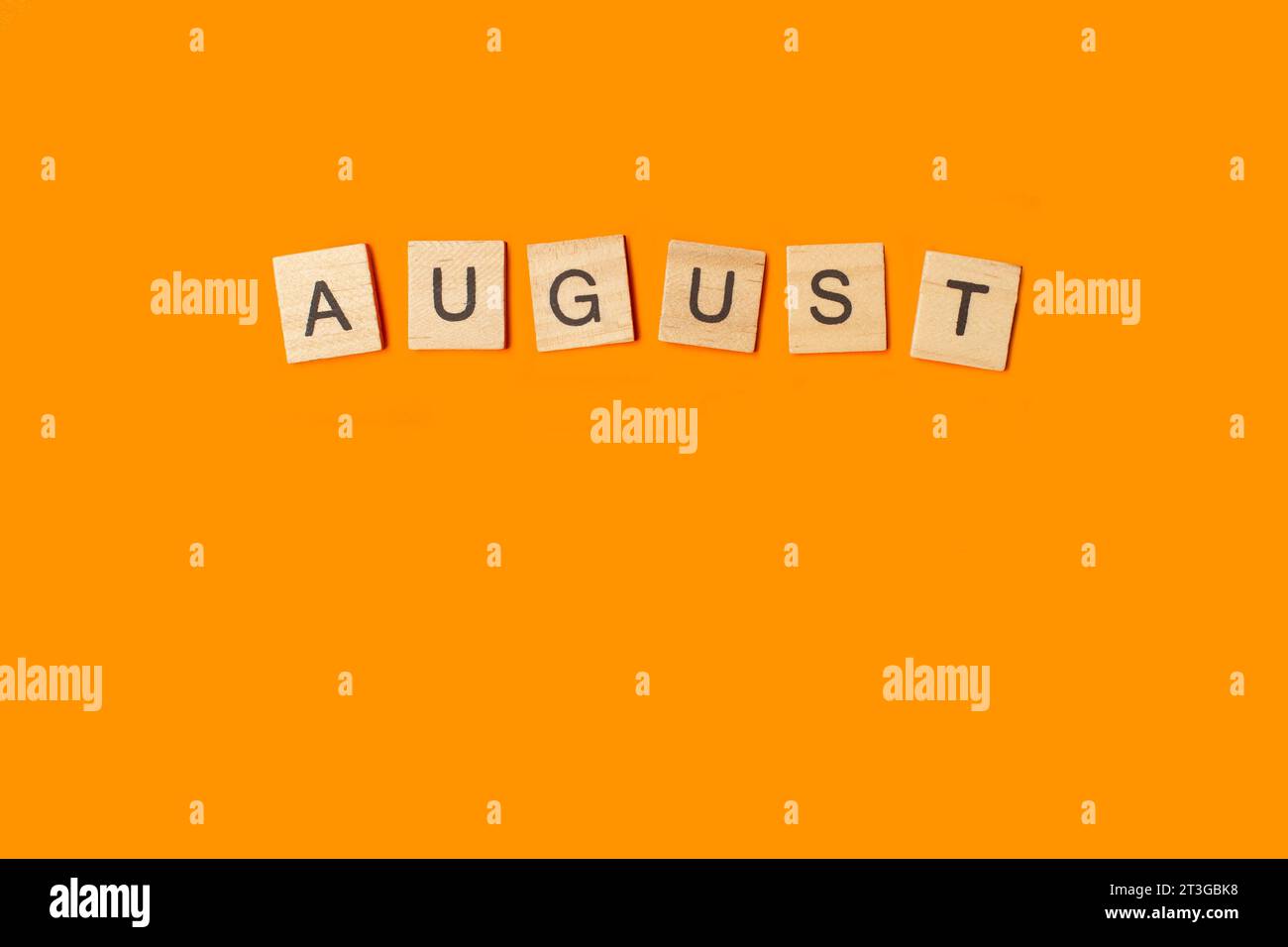 August word made with wooden letter blocks on an orange background with ...