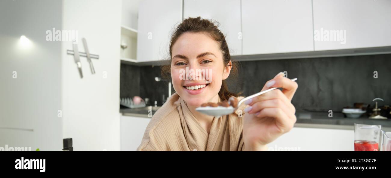 Portrait of smiling beautiful woman, feeding you spoon of cereals with ...