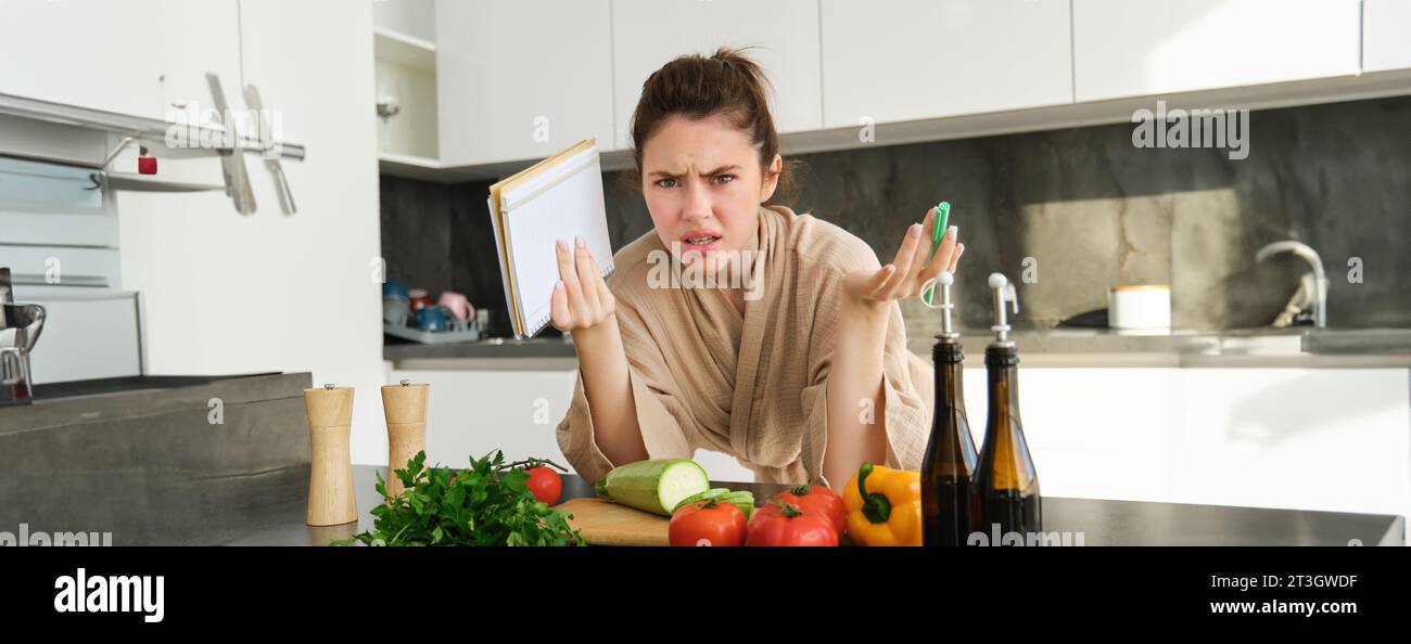 Portrait of woman cant cook, looking confused while making meal ...