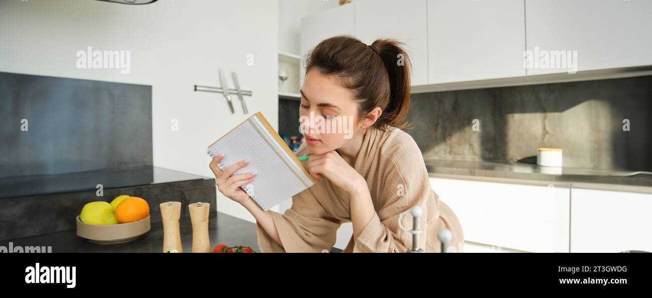 Portrait of woman checking grocery list, looking at vegetables, holding ...