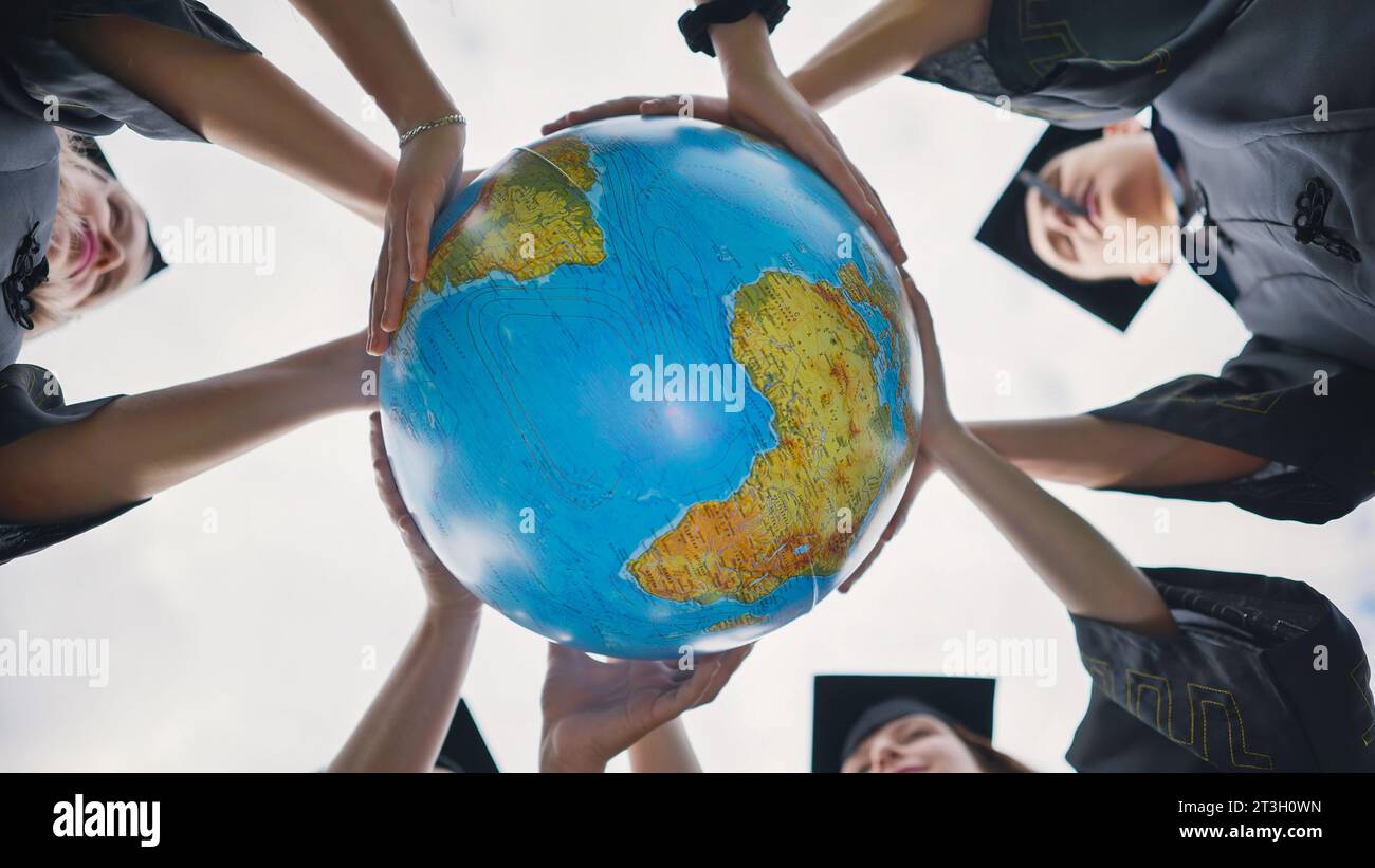 Graduating students twirl a geographic globe of the world in their ...