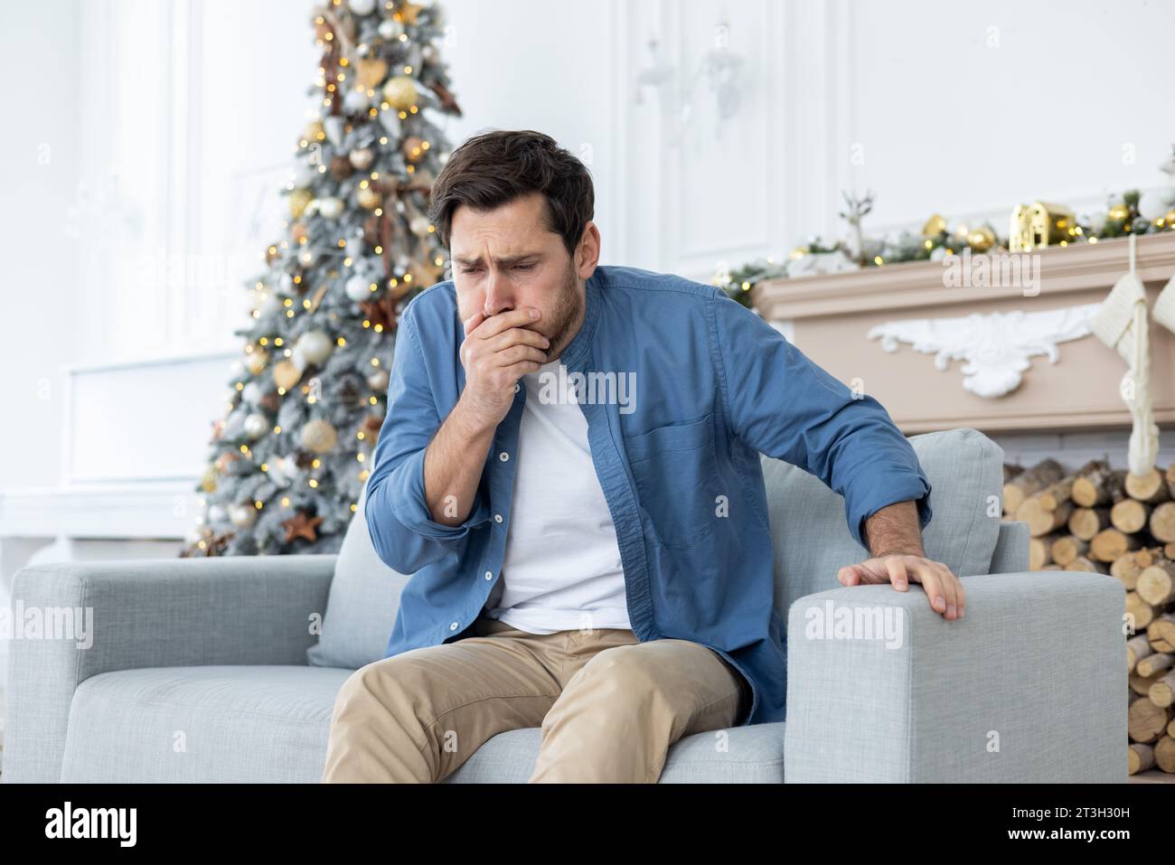 A young man sits at home on the couch during the New Year holidays and ...