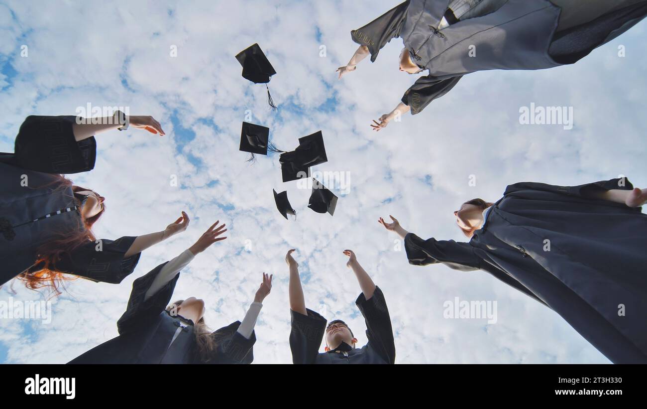 Happy group of graduated young students throwing hats Stock Photo - Alamy