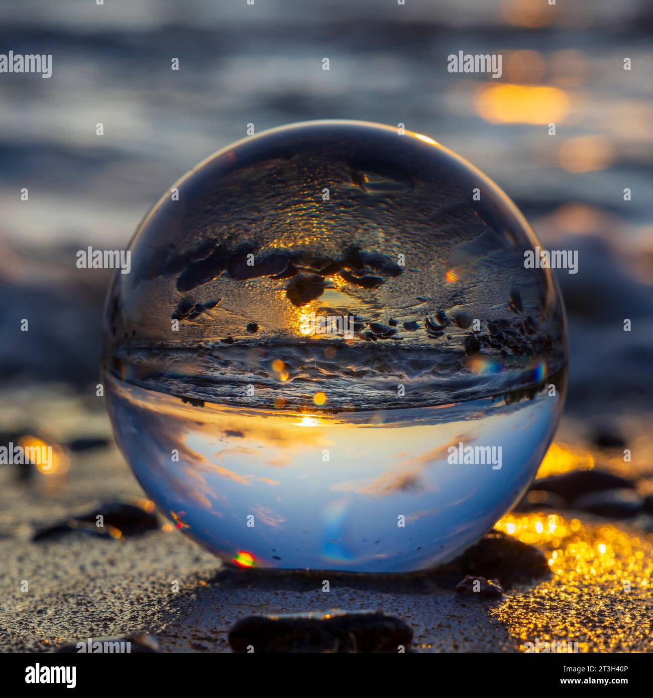 A golden sunset illuminating a glass sphere on a sandy beach Stock ...