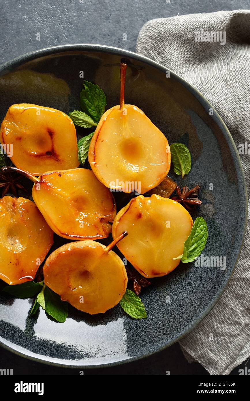 Poached pears on plate over dark stone background. Top view, flat lay ...
