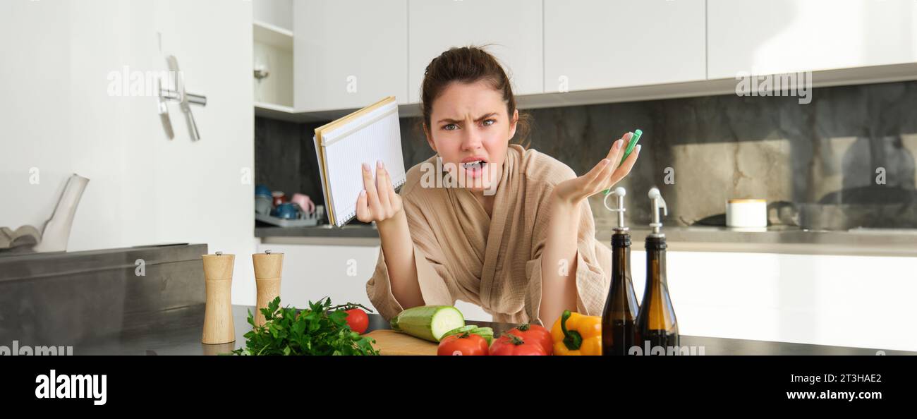 Portrait of woman with angry face, standing near vegetables and looking ...