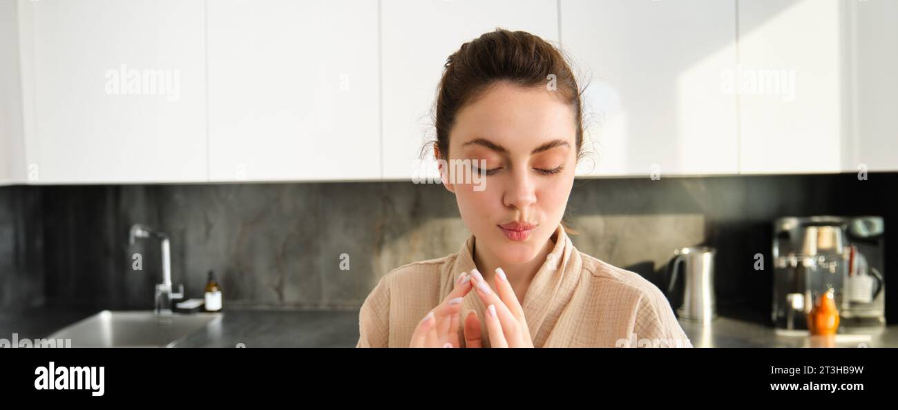 Close up of thinking woman in kitchen, wearing bathrobe, standing ...