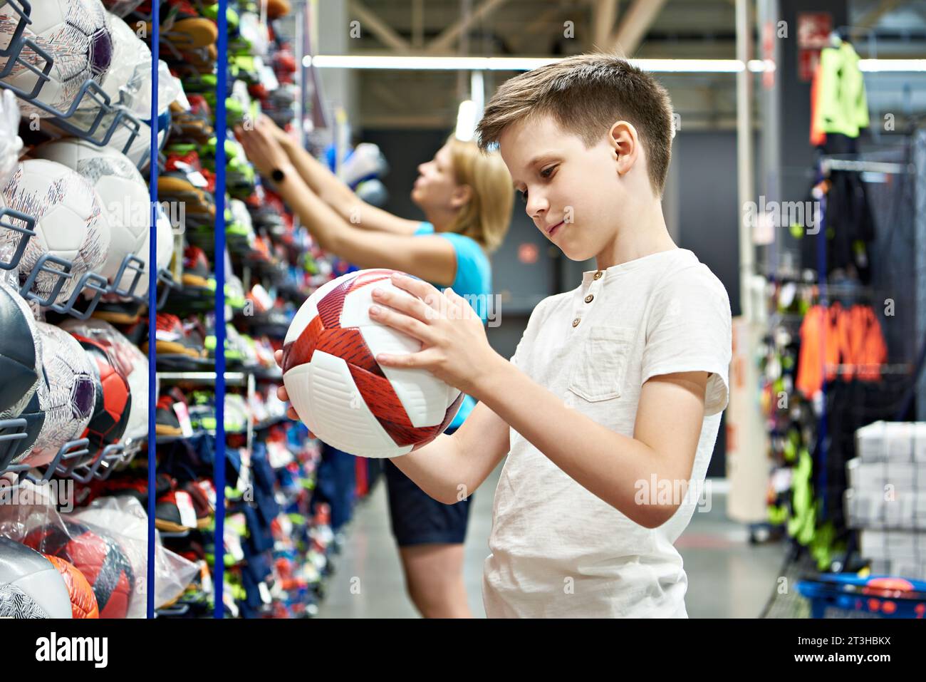 Boy soccer player with football ball in sport store Stock Photo - Alamy