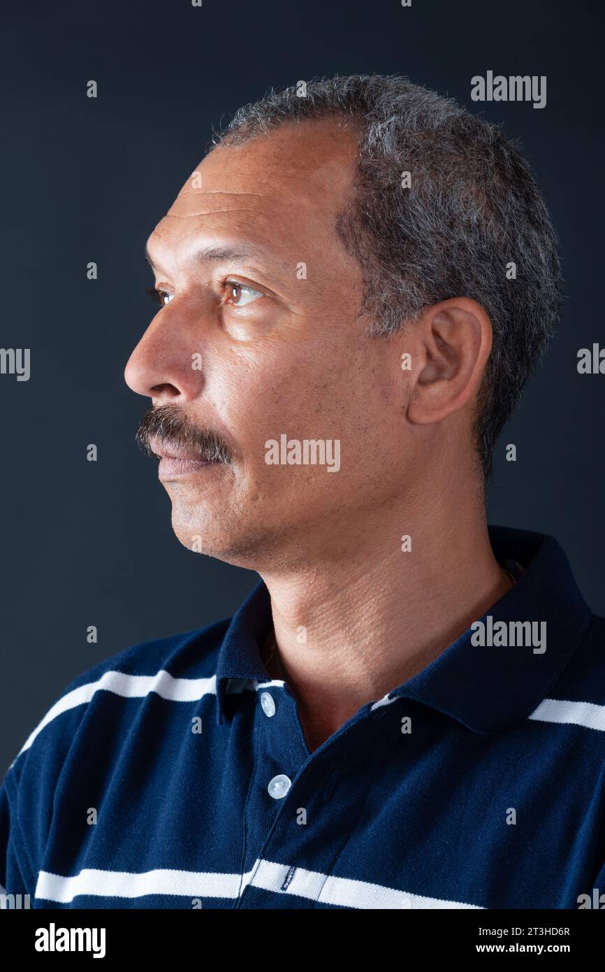 studio profile portrait of a cuban man in his fifties, dark background ...
