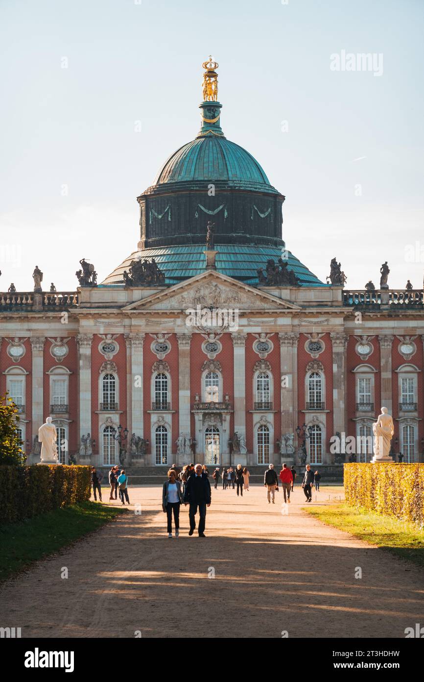visitors walk down a long path toward the New Palace in Sanssouci Park ...