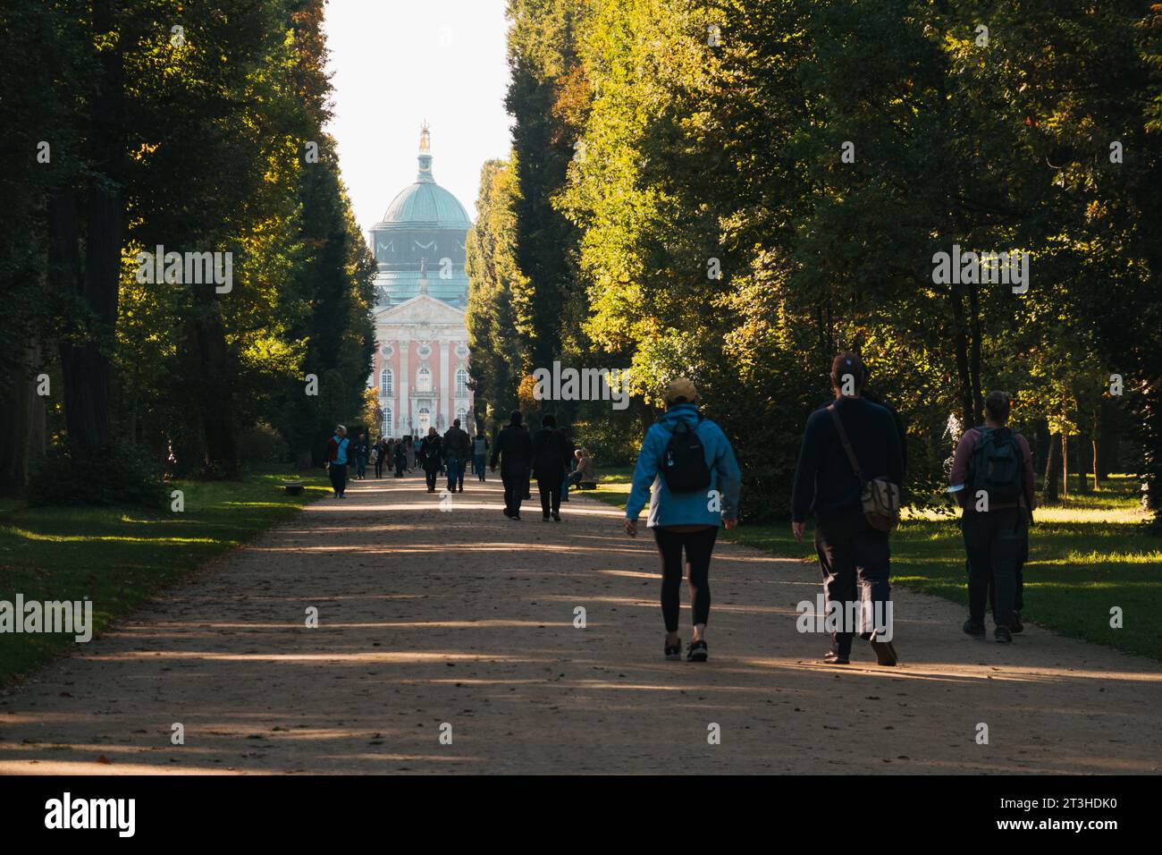visitors walk down a long path toward the New Palace in Sanssouci Park ...