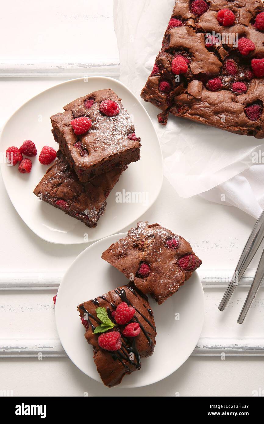 Plates and baking paper with raspberry chocolate brownie on white ...
