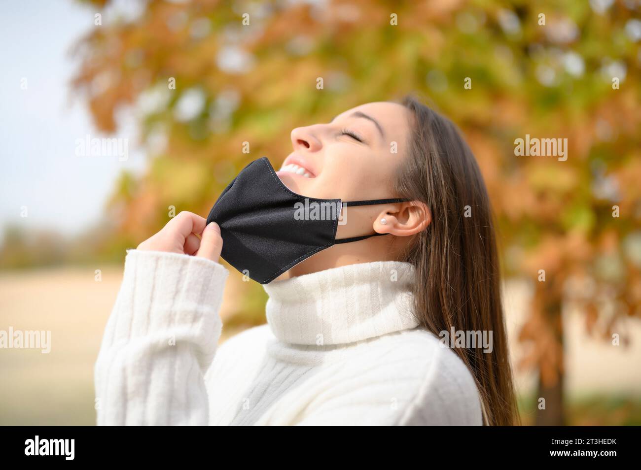 Profile of a relaxed woman taking off mask breathing fresh air in a ...