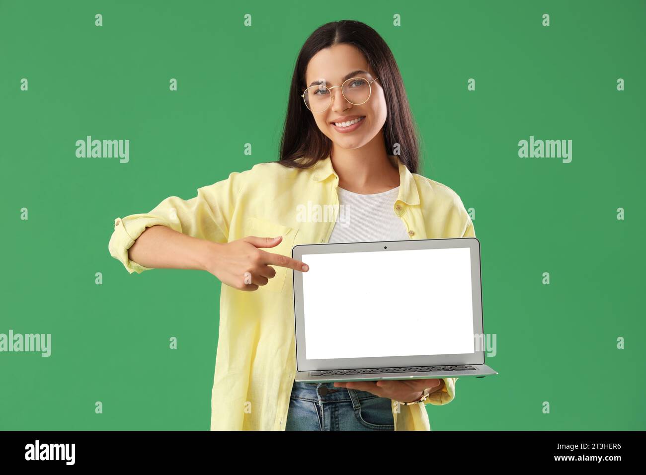 Pretty young female programmer pointing at laptop with blank screen on ...